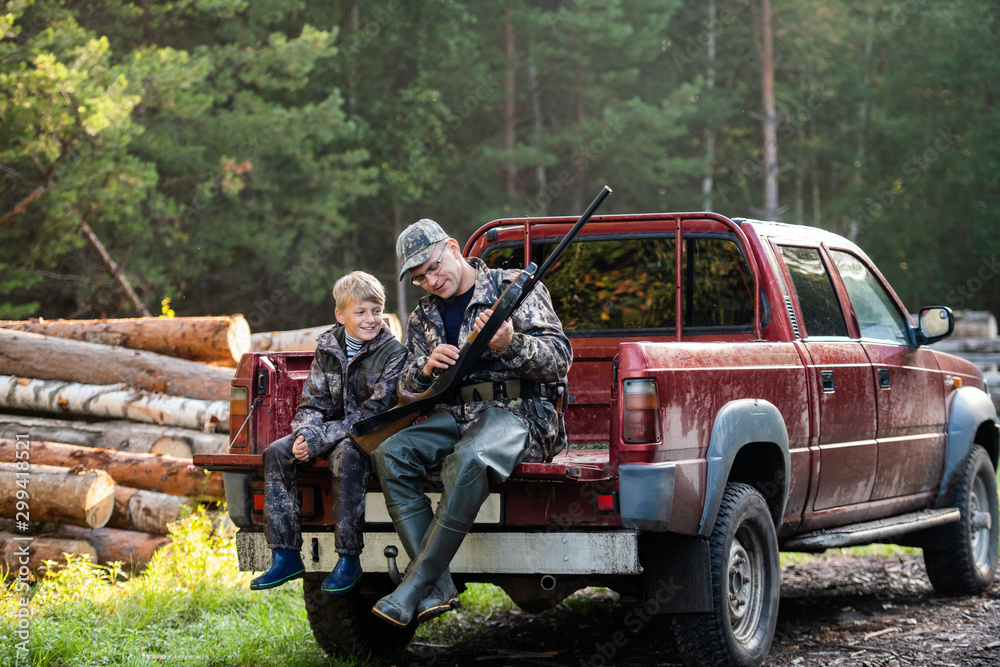 Man at his truck with his son in the forest. Hunter teaches young boy ...