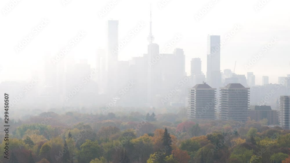 Toronto skyline in autumn rain and fog with fall colors of tree canopy ...