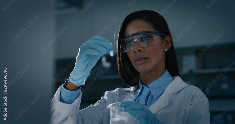 Portrait of dark skin female scientist is analyzing a liquid to extract ...