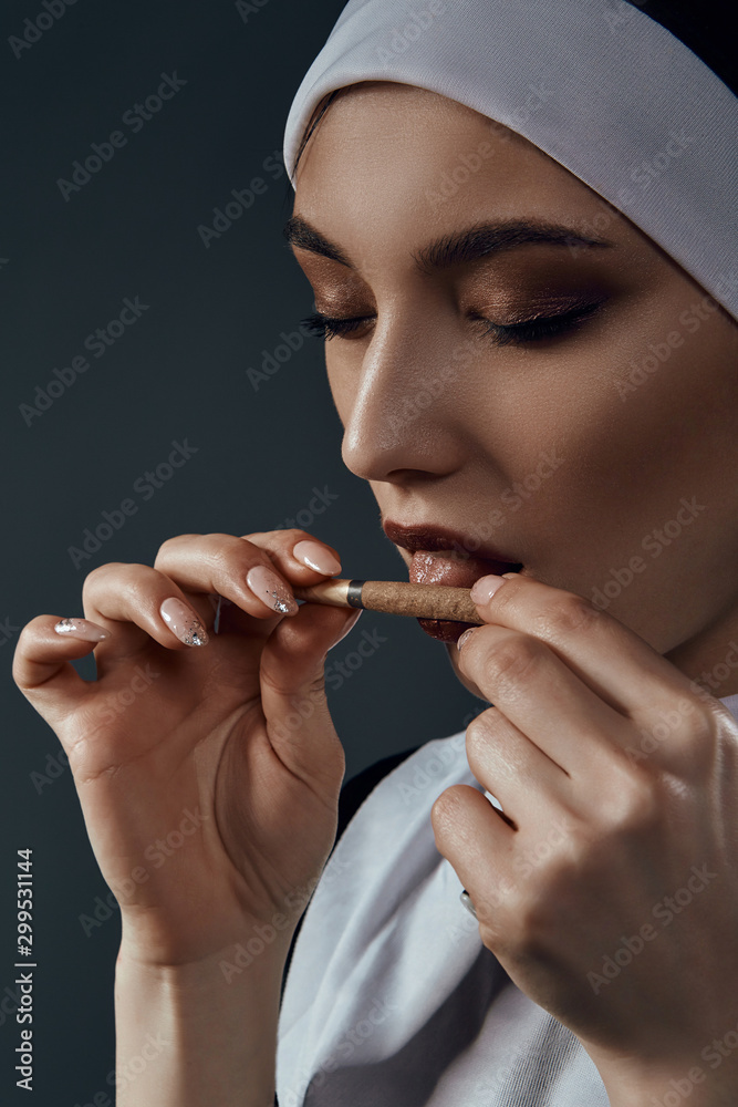 Vertical half-turn close-up portrait of a nun, posing on a black ...