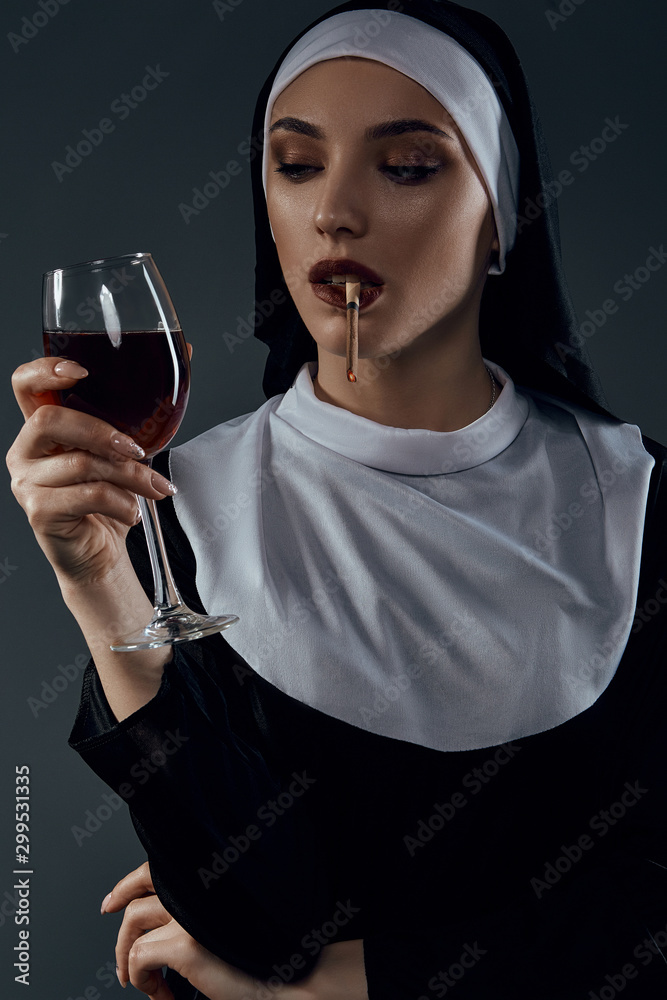Cropped shot of a nun, posing on a black background. She's wearing dark ...