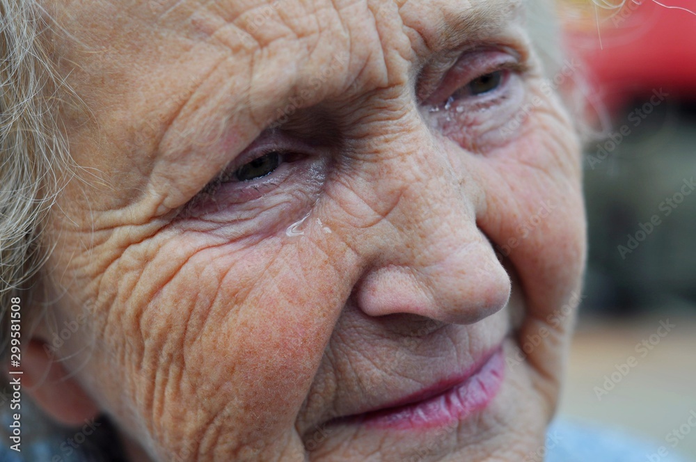 An old woman crying frantically. Tears in the eyes of an old wrinkled ...