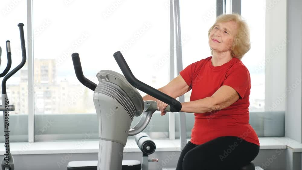 Portrait of active old woman in fitness club engaged in cardio training ...