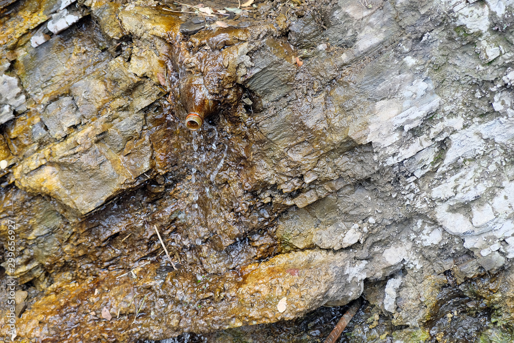 Surface of rocks wall with water flowing. Clear water flows from the ...