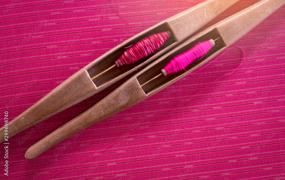 Pink yarn in weaving shuttle tool on traditional handmade fabric ...