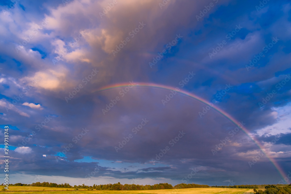 Rainbow Sky Arch on a dramatic stormy sky over yellow fields. A magical ...