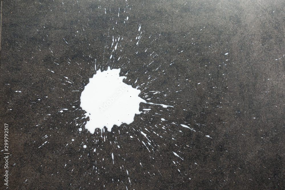 Top view of White milk spilled and splash on the dark floor surface ...