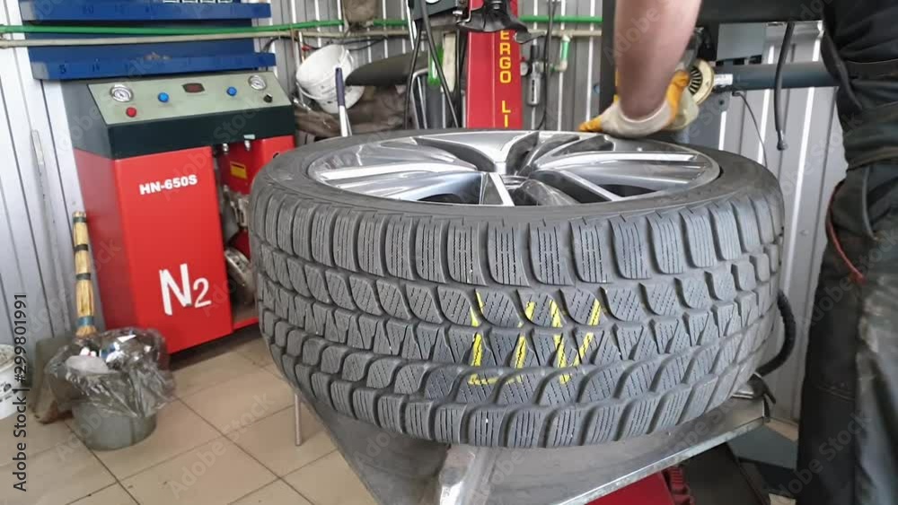 Assembly and disassembly of auto tires ; Mechanic in the workshop ...