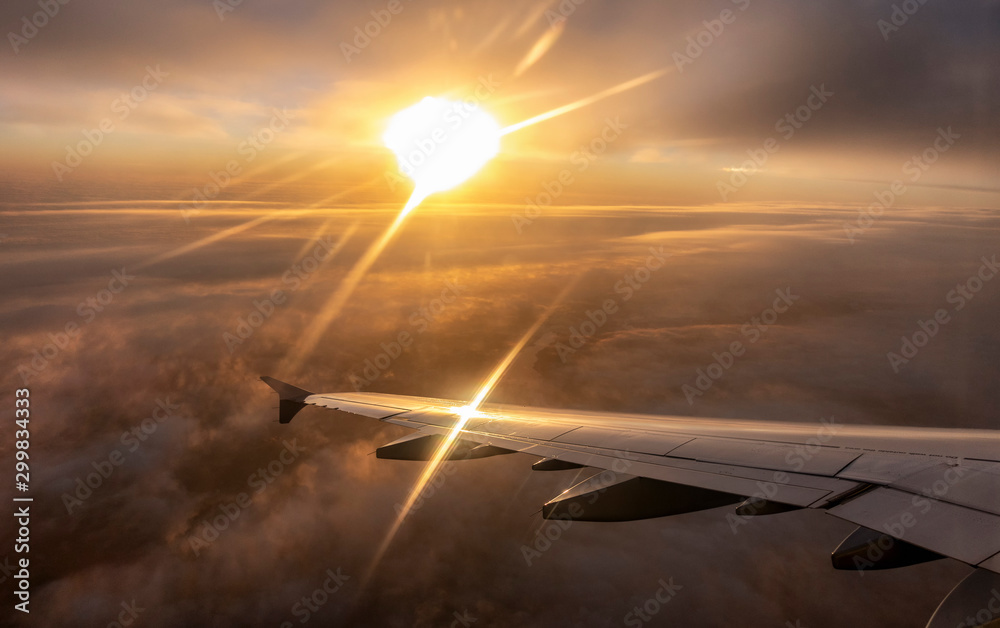 View on passenger aircraft left wing. Sun shines as a light beam over ...