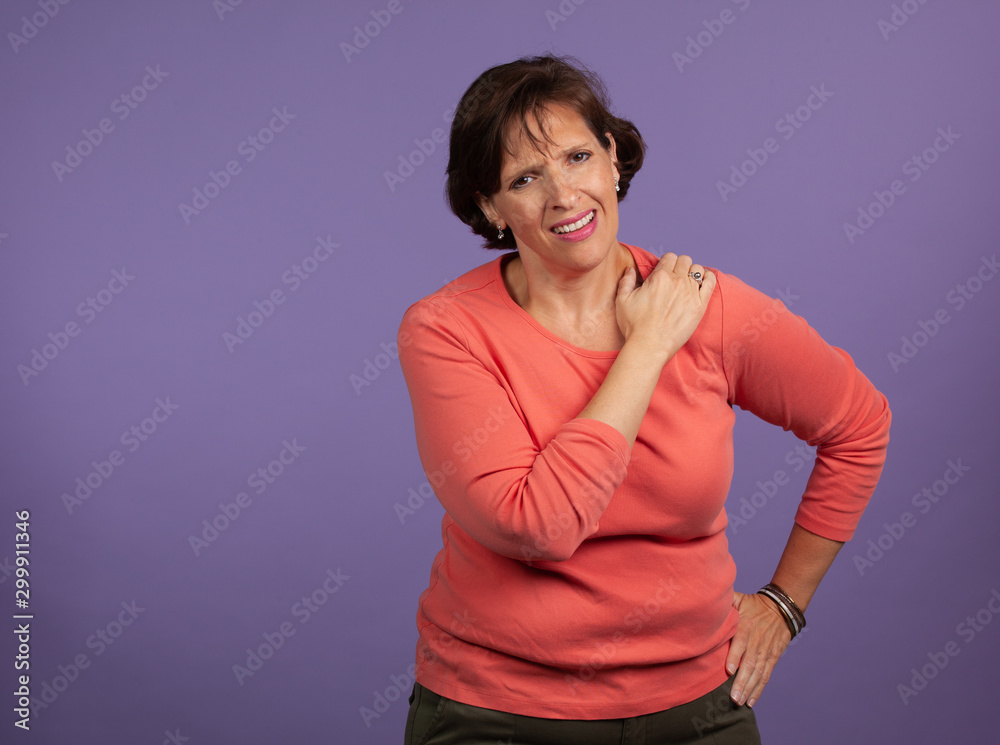 Middle Aged woman with shoulder pain holding her left shoulder and ...