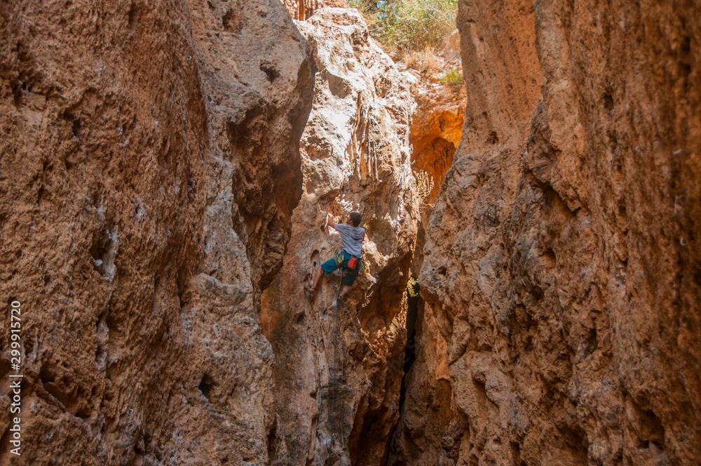 Male rock climber on challenging route in cave. Young man lead climbing ...