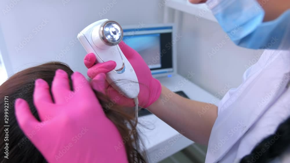 Video Stock Trichologist examines woman patient's hairs using computer ...