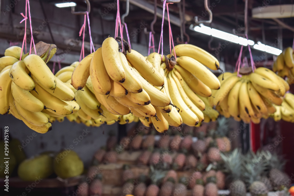 Bananas hanging of the roof in a fruit stand with pineapples and durian ...