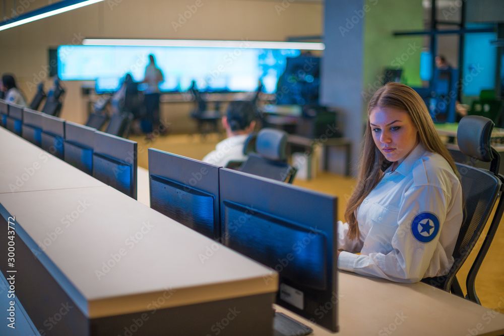 Female security guard sitting and monitoring modern CCTV cameras in a ...