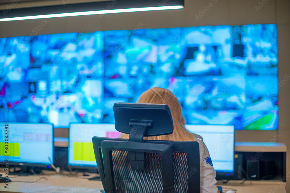 Female security guard sitting back and monitoring modern CCTV cameras ...