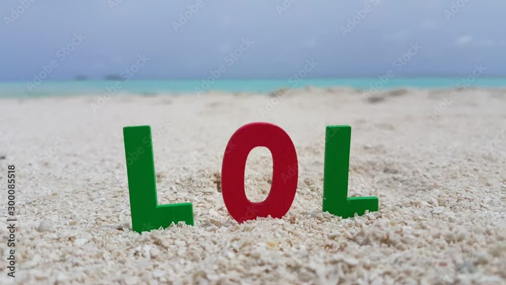 word LOL written with green and red wooden letters, on the sandy beach ...