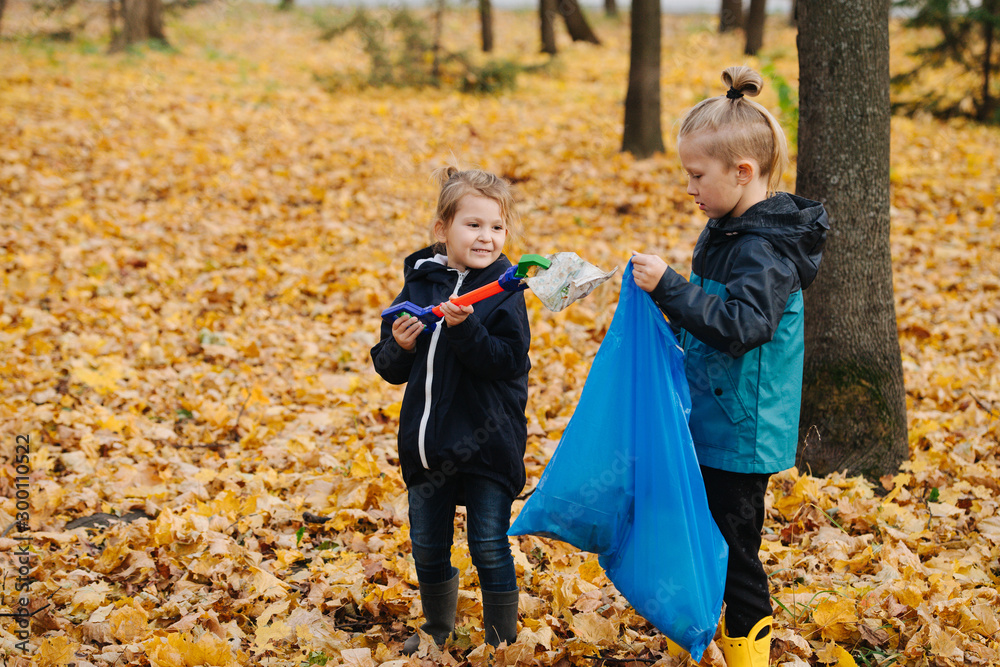 Little kid siblings collect trash using litter picker in a forest at ...