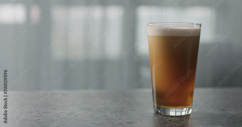 nitro light ale beer with beautiful foam in pint glass on terrazzo ...