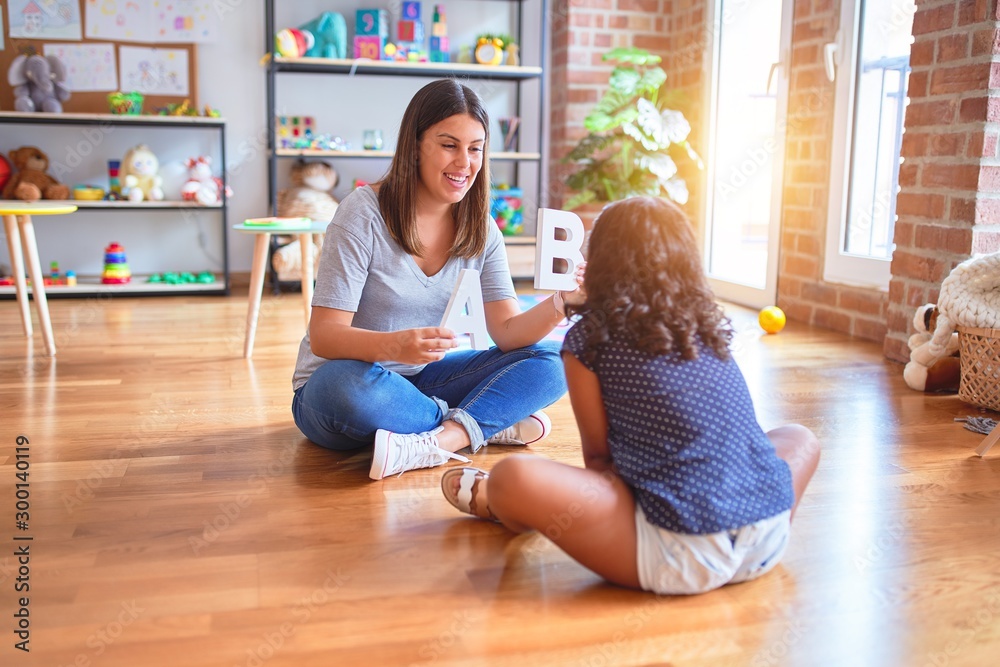 Beautiful teacher teaching alphabet to student toddler girl at ...