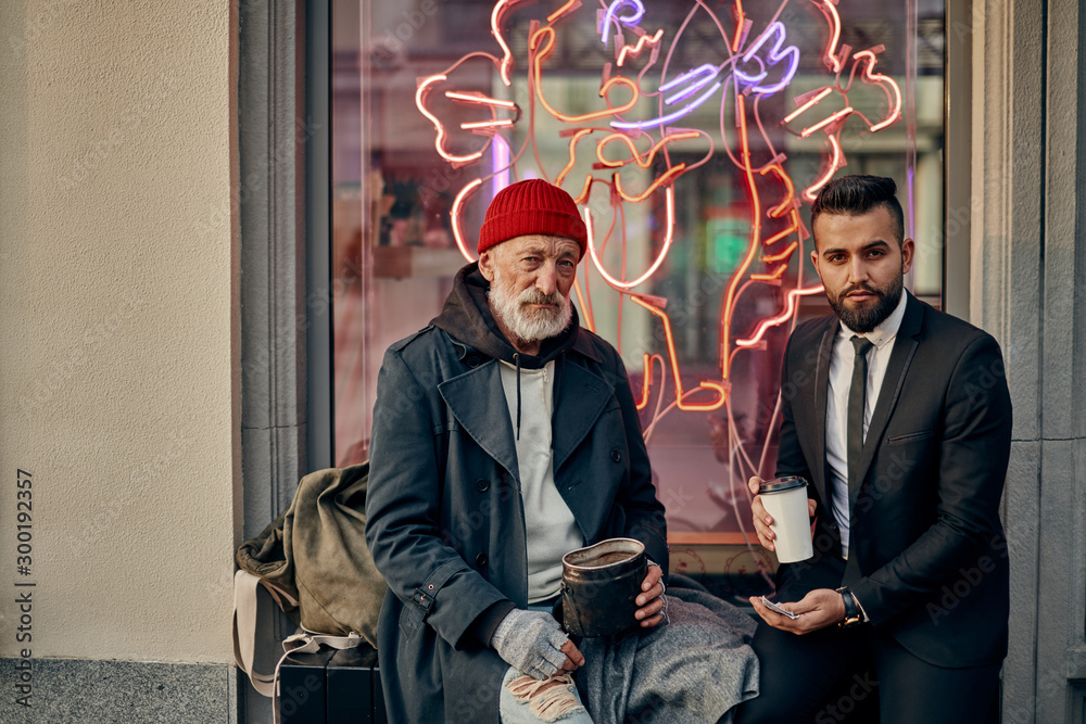 Rich man in tuxedo and homeless person in dirty clothes sitting and ...