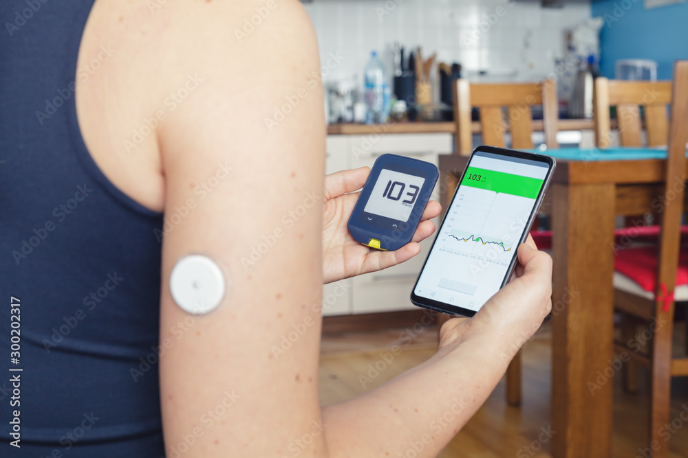 Woman comparing result of glucose level check on the traditional ...