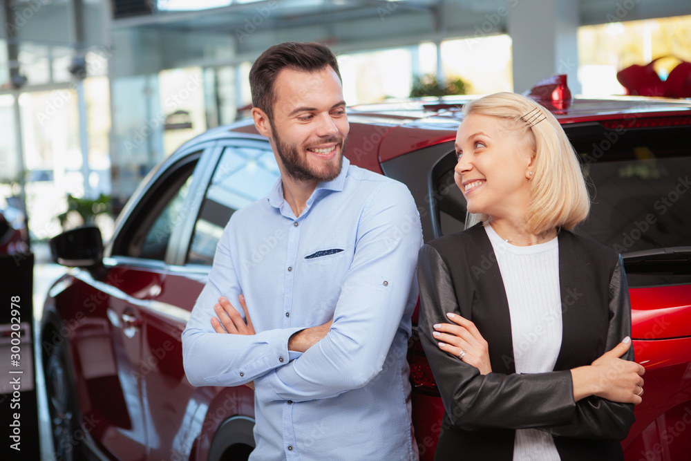 Lovely couple smiling at each other cheerfully, standing near their new ...