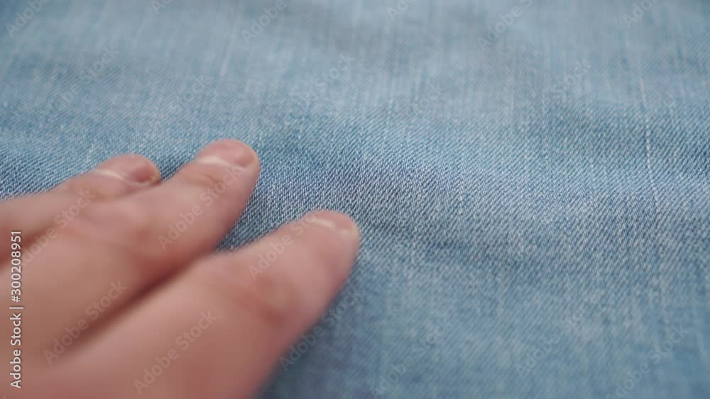 The hand gently touches the denim light blue fabric in motion ...