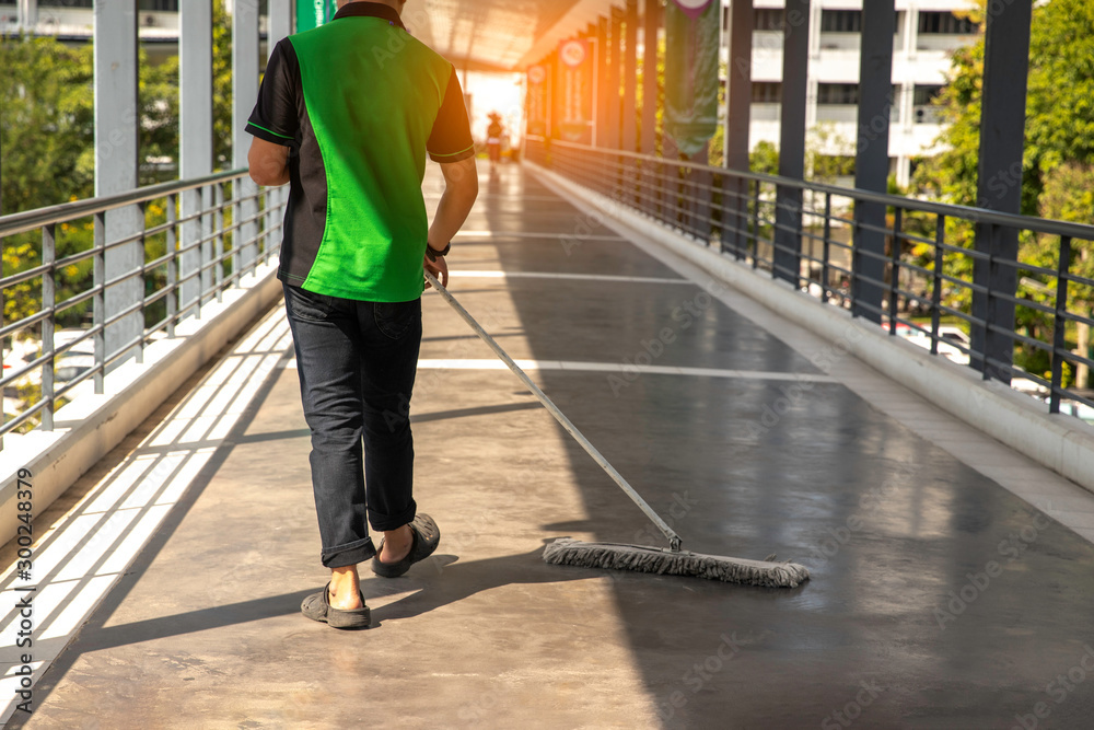 cleaner with mop and uniform cleaning hall floor of public business ...