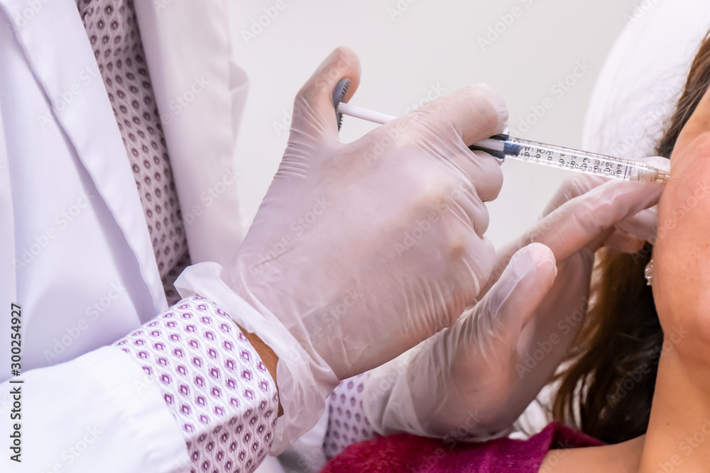 Gloved doctor hand injecting a vial of hyaluronic acid (HA) based ...