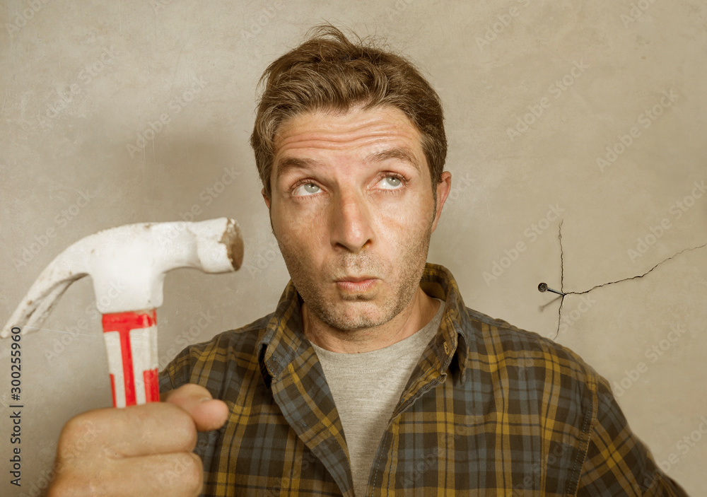 funny portrait of man holding hammer after driving a nail for hanging a ...