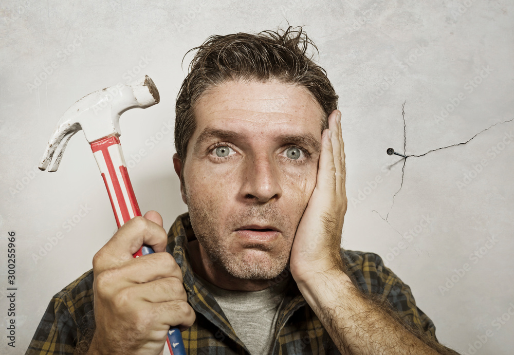 funny portrait of man holding hammer after driving a nail for hanging a ...