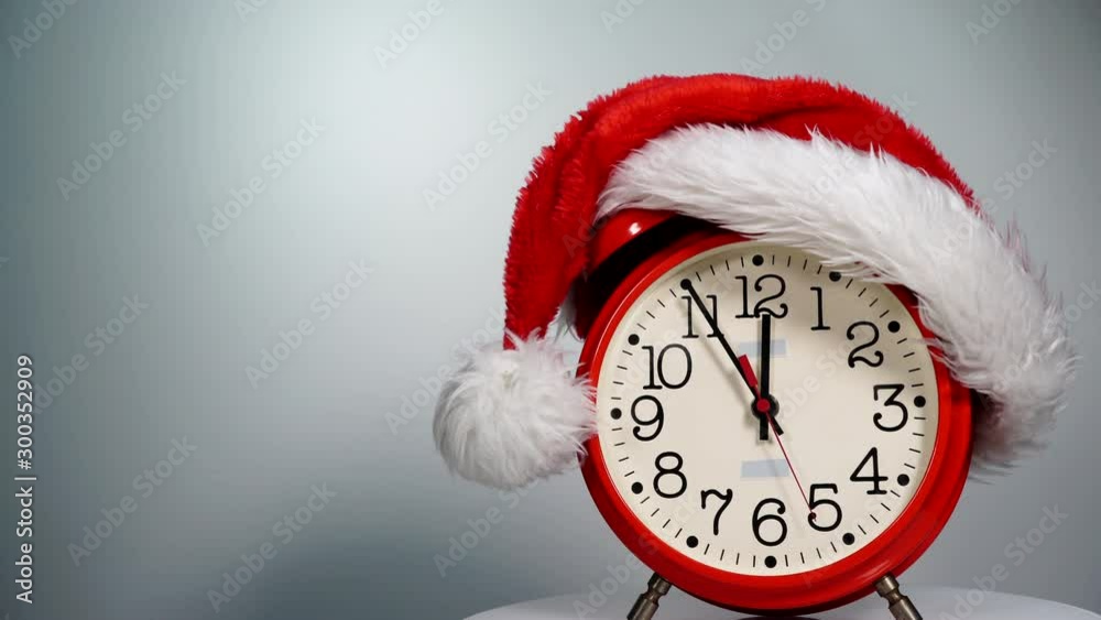 Christmas time concept. Santa Claus hat and big red clock ticking ...