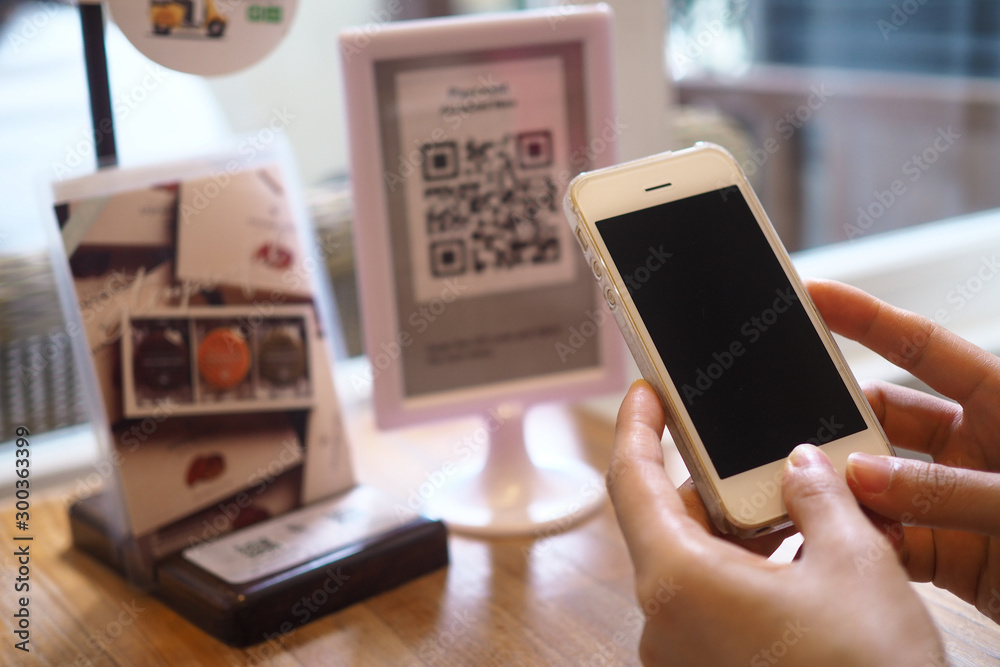 Hand using the phone to scan the QR code to receive discounts on ...