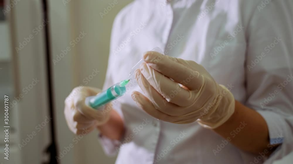 A female nurse prepares an injection syringe, fills a syringe from an ...