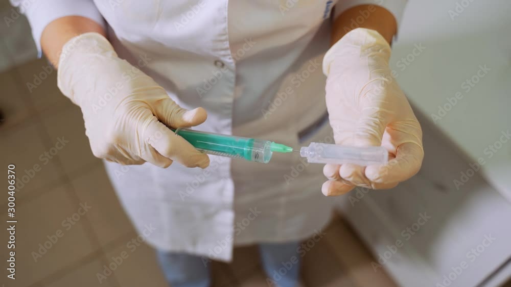 A female nurse prepares an injection syringe, fills a syringe from an ...