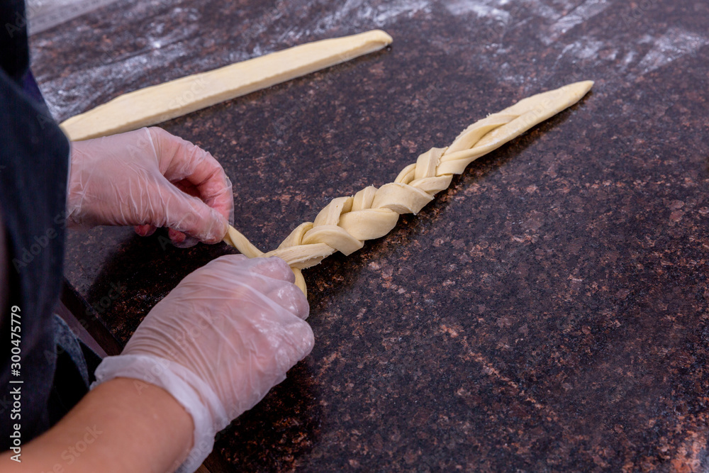 A pastry chef in the kitchen is making pastries. The chef rolls the cut ...
