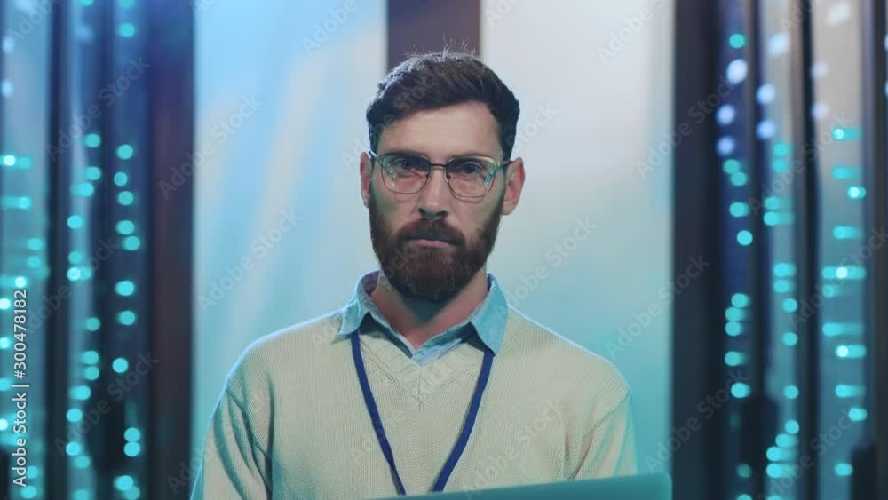 Portrait of smart bearded IT administrator working on notebook standing ...