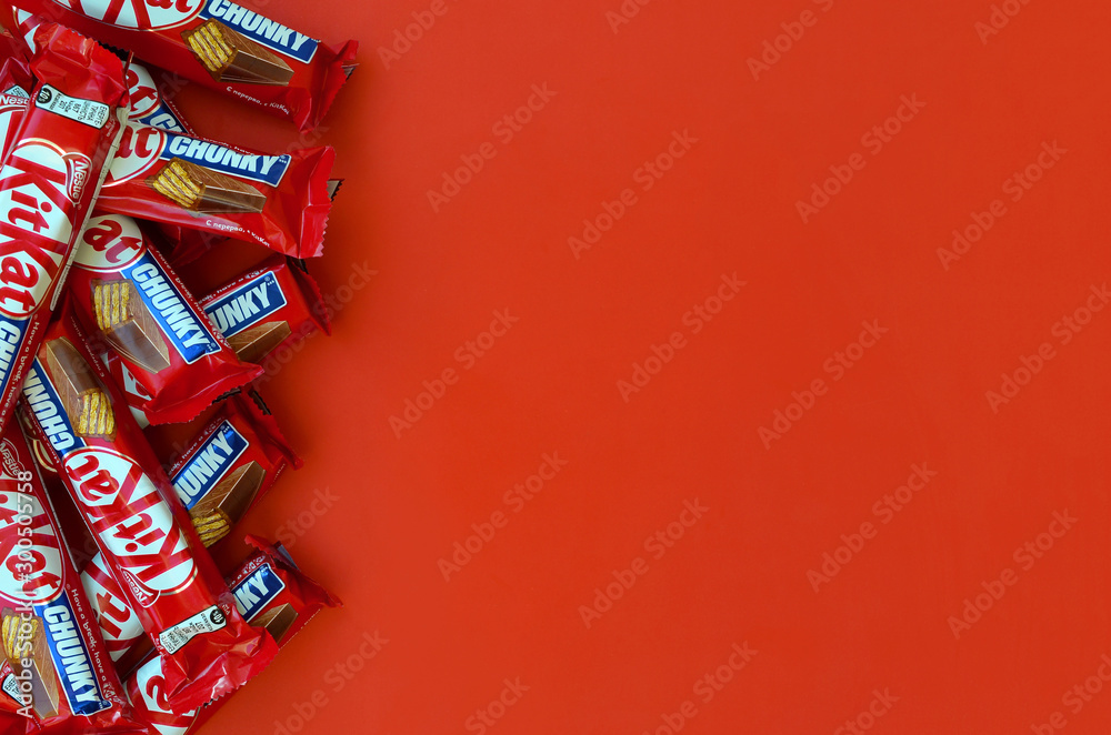 Kit Kat chocolate bars in red wrapping lies on yellow background is now ...