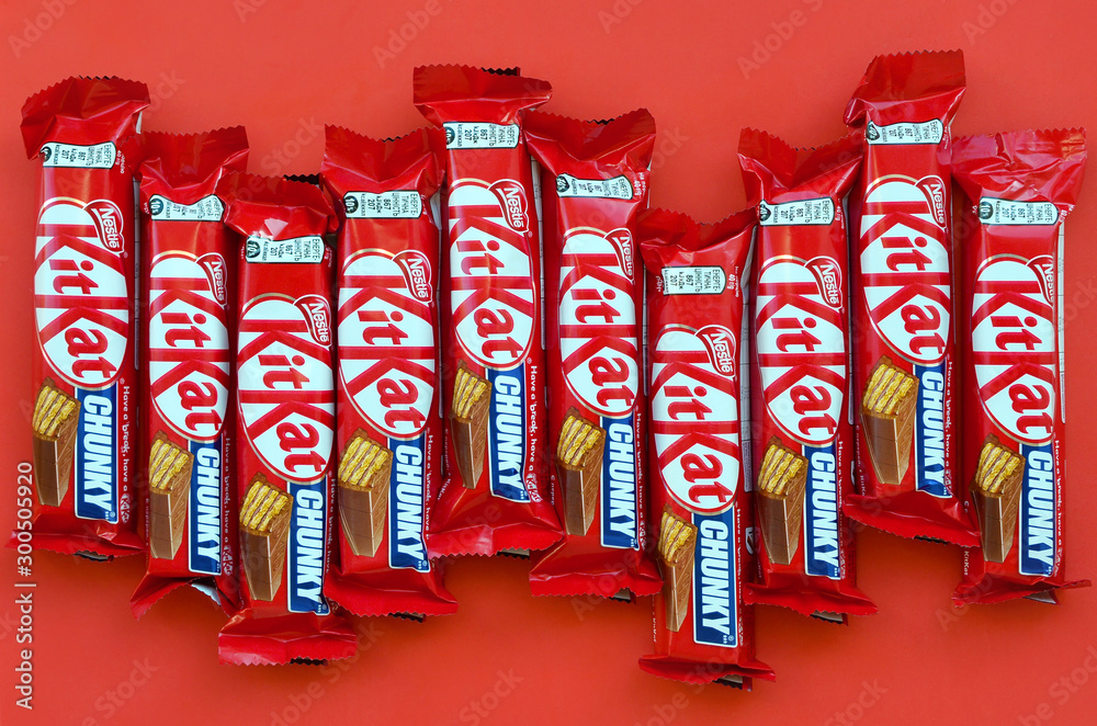 Kit Kat chocolate bars in red wrapping lies on yellow background is now ...