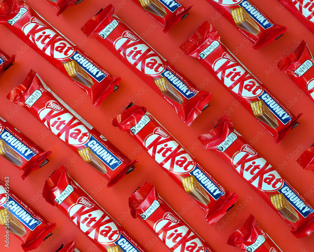 Kit Kat chocolate bars in red wrapping lies on yellow background is now ...