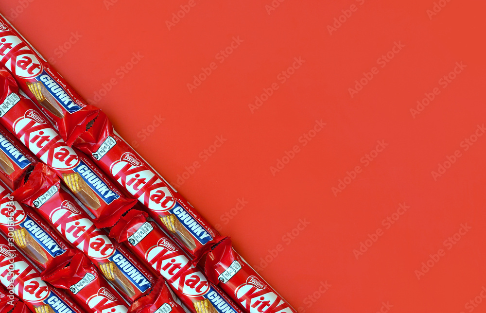 Kit Kat chocolate bars in red wrapping lies on yellow background is now ...
