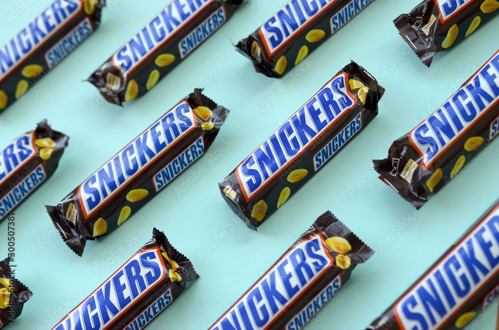 Many Snickers chocolate bars lies on pastel blue paper. Snickers bars ...