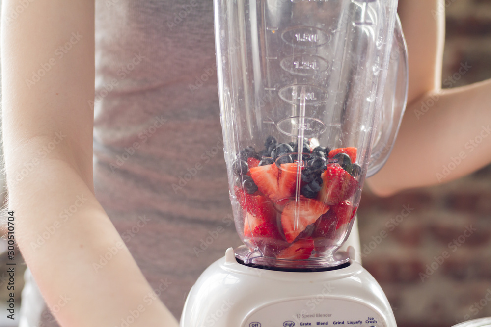 Female fitness model demonstrates losing cut fruit and berries into a ...