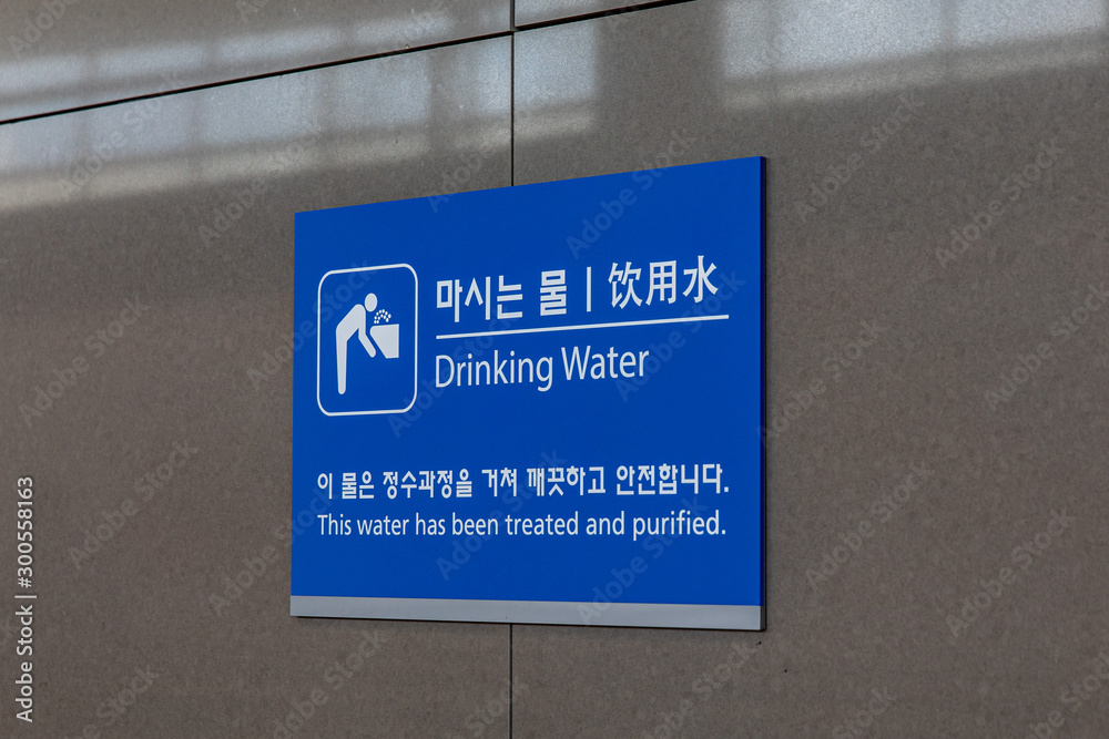 Blue posted sign on a stone wall read "Drinking Water" and "This was ...