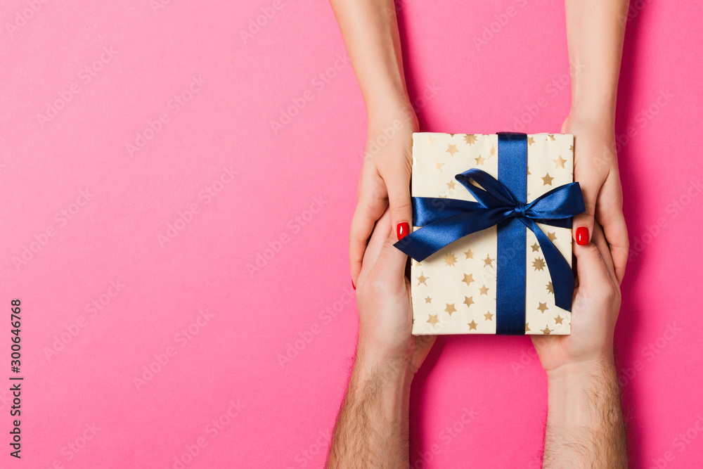 Top view of a man and a woman holding a gift on colorful background ...