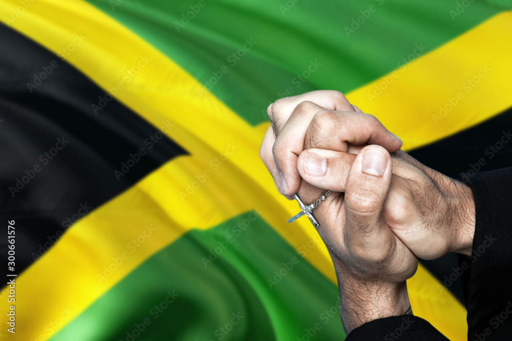 Jamaica flag and praying patriot man with crossed hands. Holding cross ...