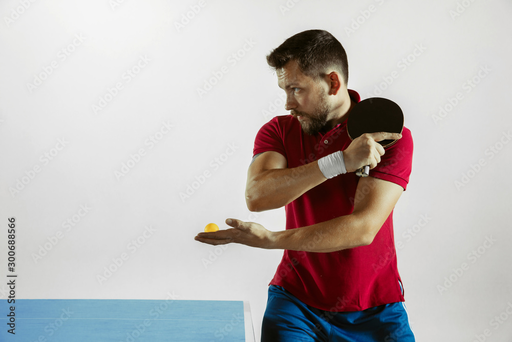 Young man plays table tennis on white studio background. Model in ...