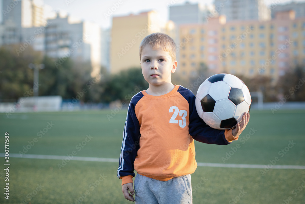 boy playting football on the field with gates. Active child in summer ...