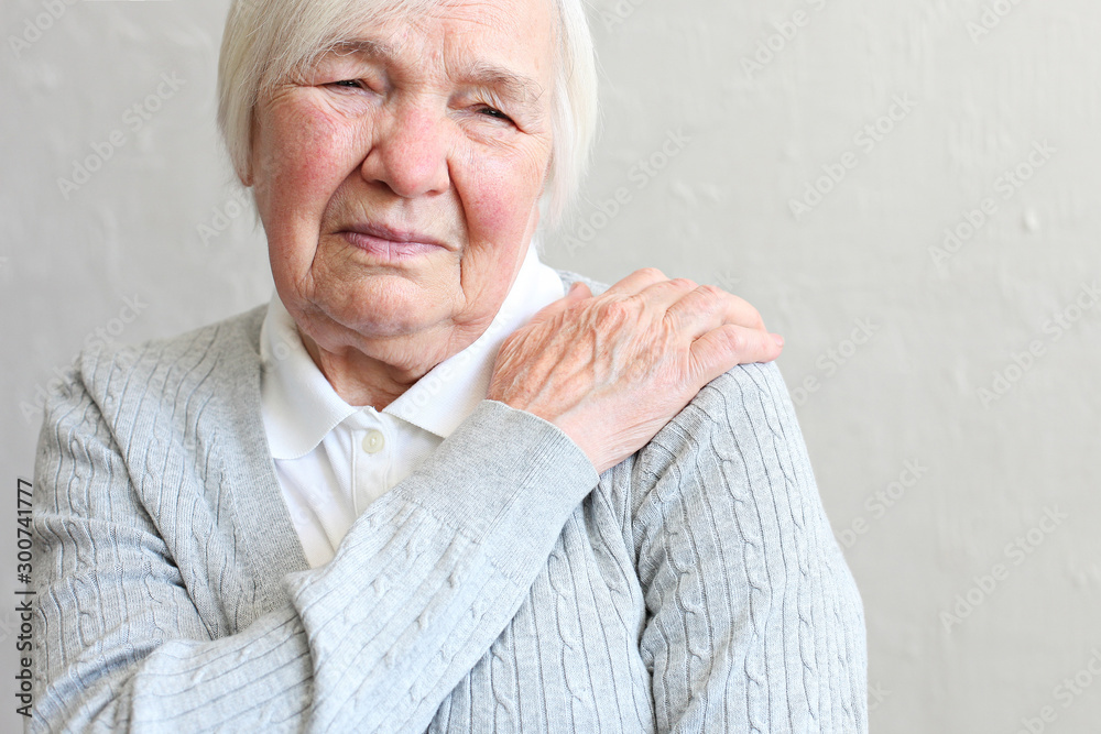 Elderly woman massaging the shoulder easing the aches. Joint pain ...