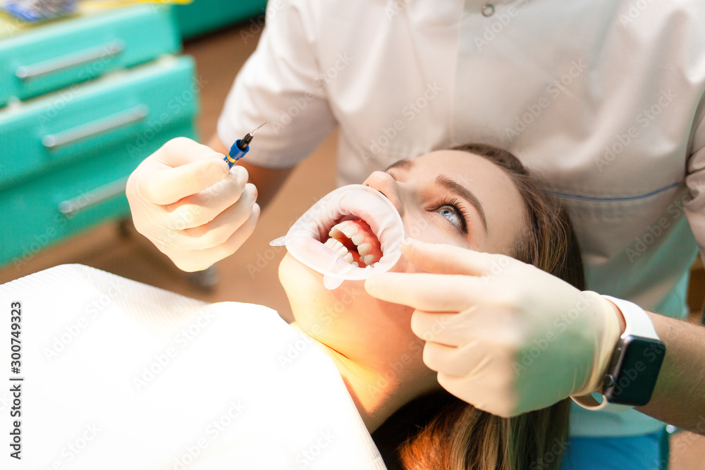 Patient with cheek retractor lies on the dental chair during the ...